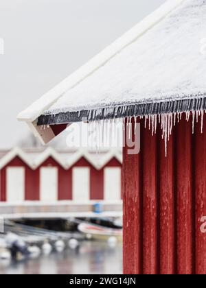 Icicles hang from the snow-covered roof of an old wooden house Stock ...