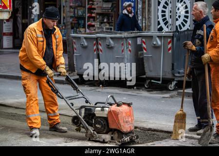 Workers in orange uniforms and protection equipment fixing and patching ...