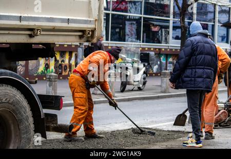Workers in orange uniforms and protection equipment fixing and patching ...
