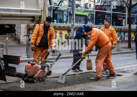 Workers in orange uniforms and protection equipment fixing and patching ...