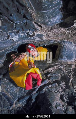Female caver crawling in narrow stream passage of Clearwater Cave ...