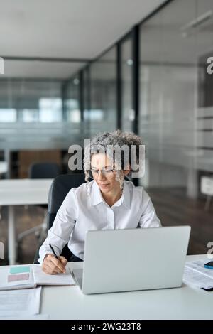 Middle age businesswoman working using laptop and talking on the ...