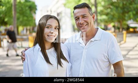 Confident father sharing sunny, joyful hug with smiling daughter at ...