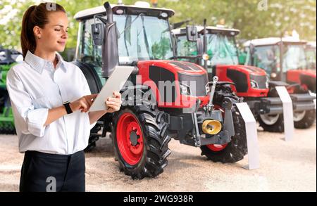 Female sales representative showcasing agricultural tractors with ...