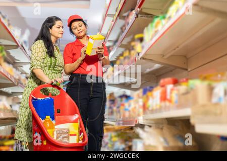 Happy young indian female cashier in red hat, shirt showing qr code ...