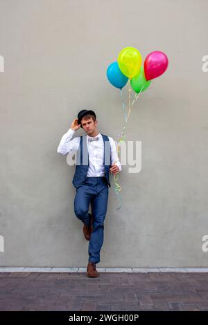 Man with colored balloons on sidewalk vertical Stock Photo - Alamy