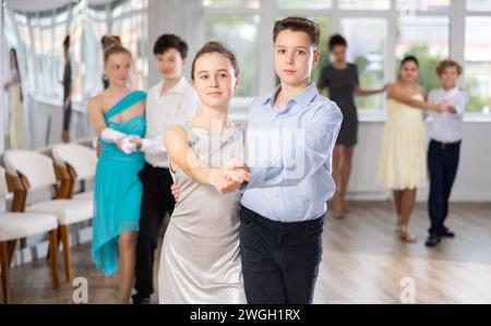 Adolescent ballroom dancers practicing elegant dance moves in pairs ...
