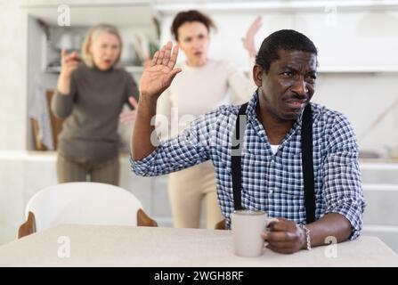 Tense man listens to two women shouting at him in kitchen Stock Photo ...