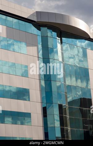 generic office building with glass facade reflecting sky and clouds ...