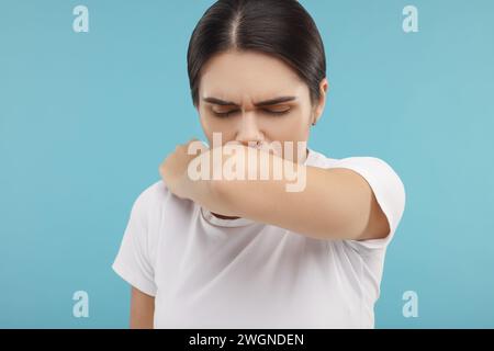 Woman coughing on light blue background. Cold symptom Stock Photo - Alamy