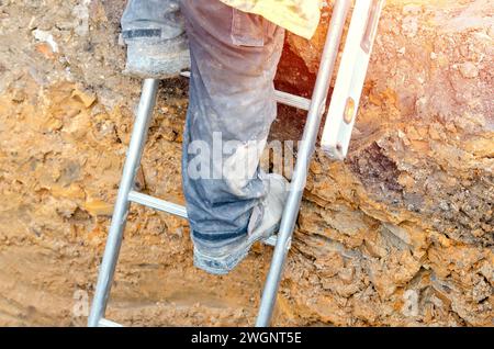 Builder going up the ladder to get out of trench Stock Photo - Alamy