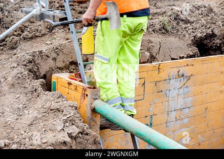 Groundworker builder using steps ladder to get out of the deep drainage ...