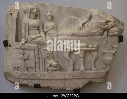 Funeral feast: a woman, a man and servants. Inscription in Greek. Stele ...