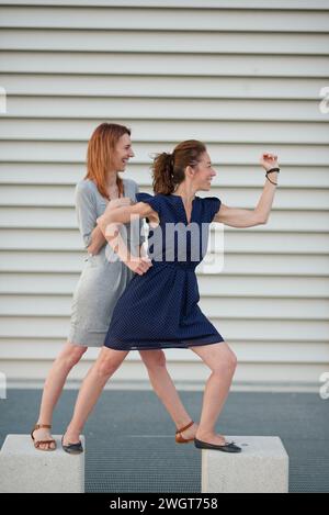 Two young adult women friends smiling and taking a selfie in a busy ...