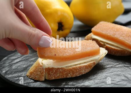 Making sandwich with quince paste. Woman spreading butter on bread at ...