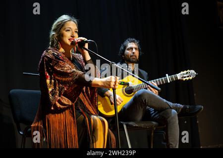 "Female flamenco singer performing with male guitarist on a dimly lit ...