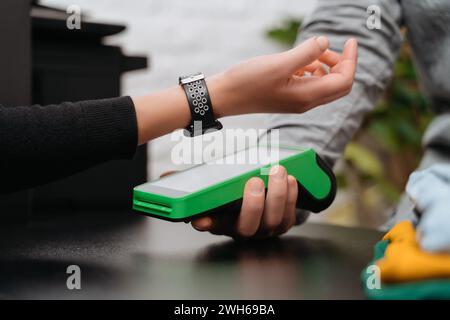 Woman using terminal for contactless payment with smart watch in shop ...