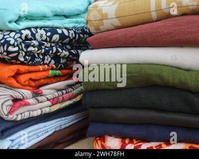 Folded cloth in piles, various types of clean clothes arranged neatly ...