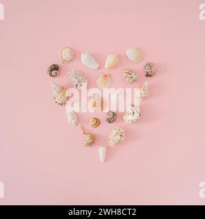 Heart made of pink sea shells on sand with space for text. Valentine's ...