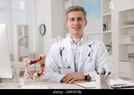 Gastroenterologist with anatomical model of large intestine at table in ...