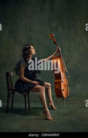 Elegant, passionate musician, beautiful woman in black dress sitting ...