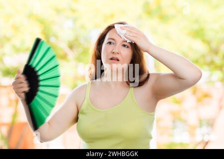 Sad woman fanning and sweating suffering a heat stroke in a park Stock ...