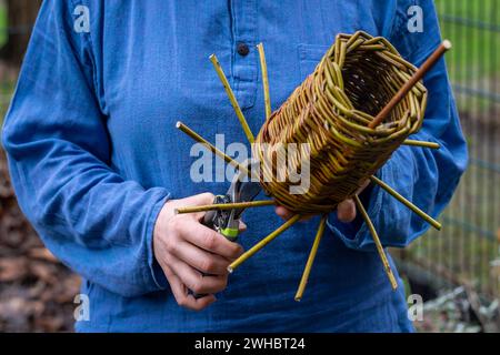 Craftswoman making woven bird house, weaving wicker basket from willow ...