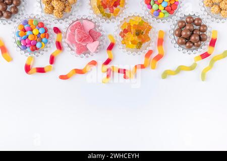 Sweets on and next to small glass plates in rows on a white background ...