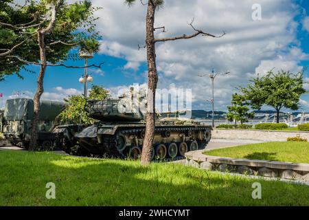 Side view of M48 tank on display at seaside park under blue cloudy sky ...