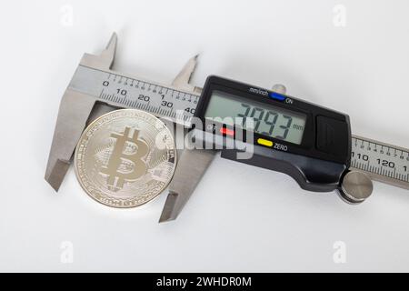 Electronic caliper measures the diameter of a Bitcoin coin, white ...