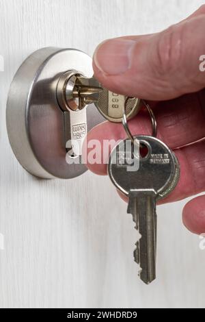 A hand unlocks the front door with a key. Man using keys and locking ...