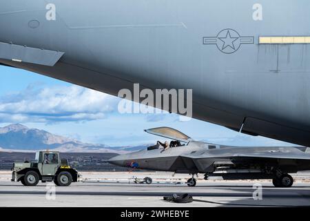 An MB4 tow tractor pulls an F-22 Raptor to be refueled by a C-17 ...