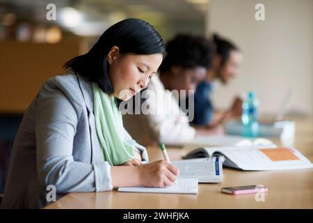 Asian women reading book at desk with laptop computer for professional ...