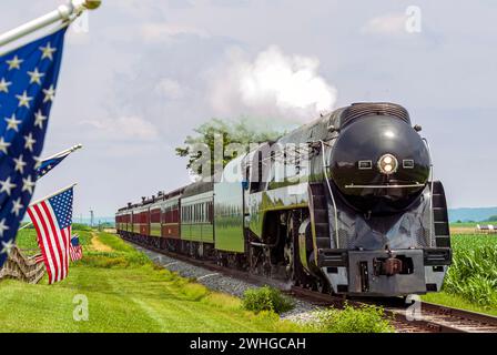 A Restored Steam Passenger Train Approaches As American Flags Wave on a ...