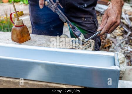 Roofer welding stainless gutter with an copper soldering iron. Closeup ...