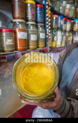 Spice seller holding a jar of turmeric Stock Photo - Alamy