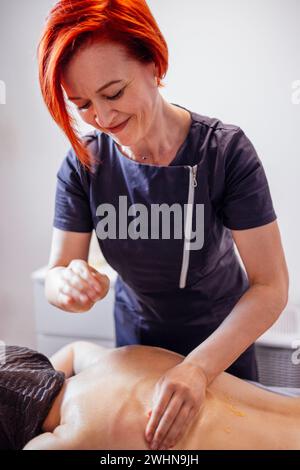Professional masseuse in white uniform performs relaxing leg massage on ...