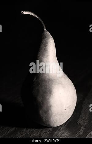 A Bosc pear (Pyrus communis 'Bosc') on a table with a dark background ...