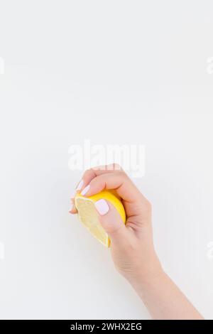 Female hand squeezing half of lemon on white background Stock Photo - Alamy