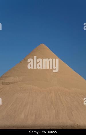 Mound of fine excavated light tan sand against blue sky at construction ...
