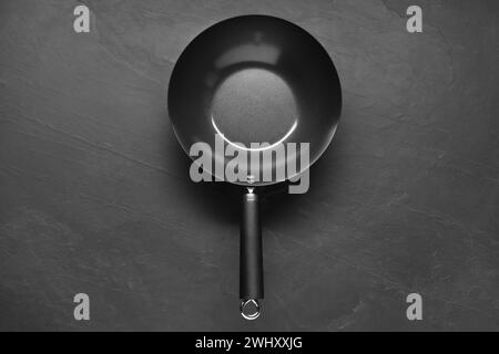 Empty iron wok on black textured table, top view. Chinese cookware ...