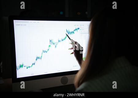 Young asian broker using the computer to analyze cryptocurrency ...