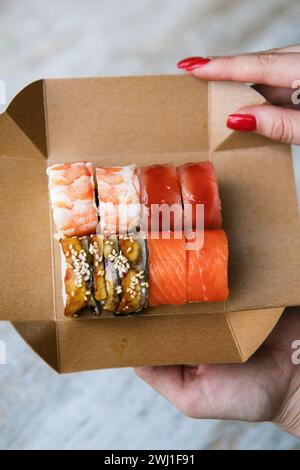 sushi set on packing box in hand on pizza background. street food Stock ...