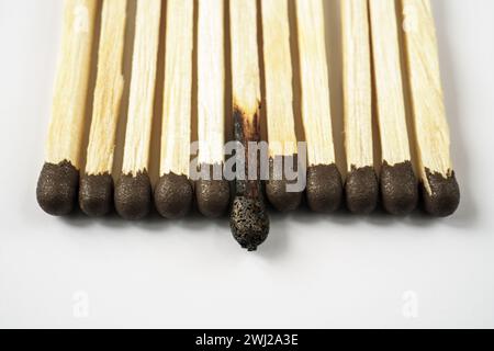 Whole and burnt matches lined up in a row isolated on a white ...