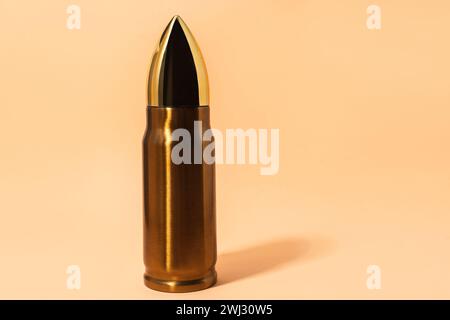One big shiny bullet against beige background Stock Photo - Alamy