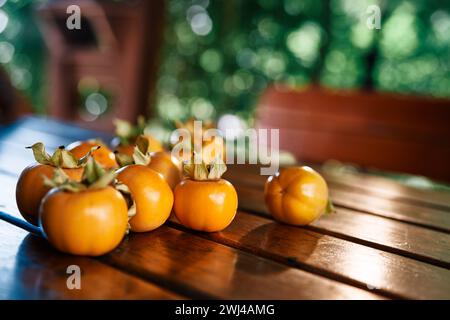 Fresh ripe persimmons lie on a wooden table near the bench in the ...