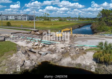 Road construction. Excavator repairing destroyed bridge after hurricane ...