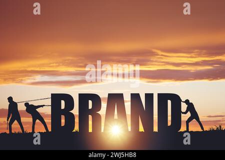 Silhouettes of people drawing the word BRAND on a sunset background ...