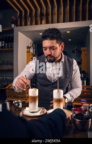 Barista decorating latte macchiato. Coffee speciality in tall glass ...