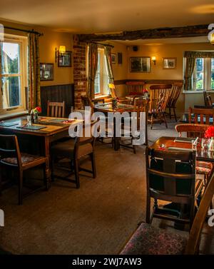 The interior of a public house which is warm and inviting with tables ...